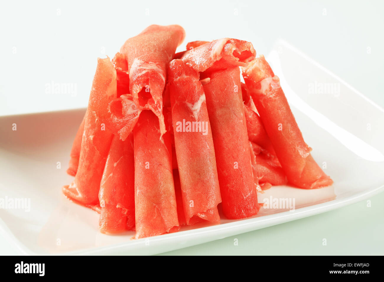 Thin slices of raw beef meat - rolled up Stock Photo - Alamy