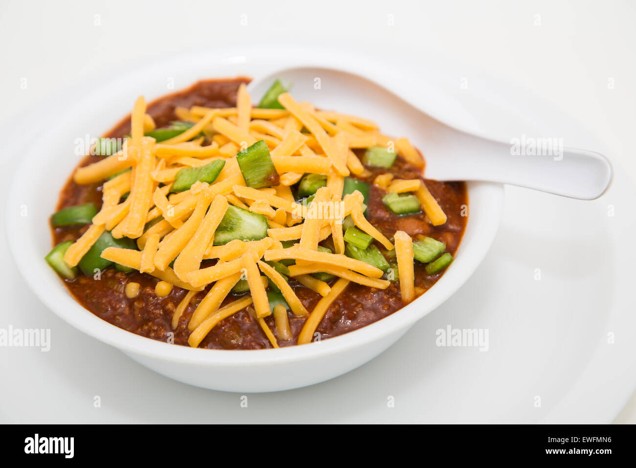 A white bowl of chilli with meat and beans and green poblano chile ...