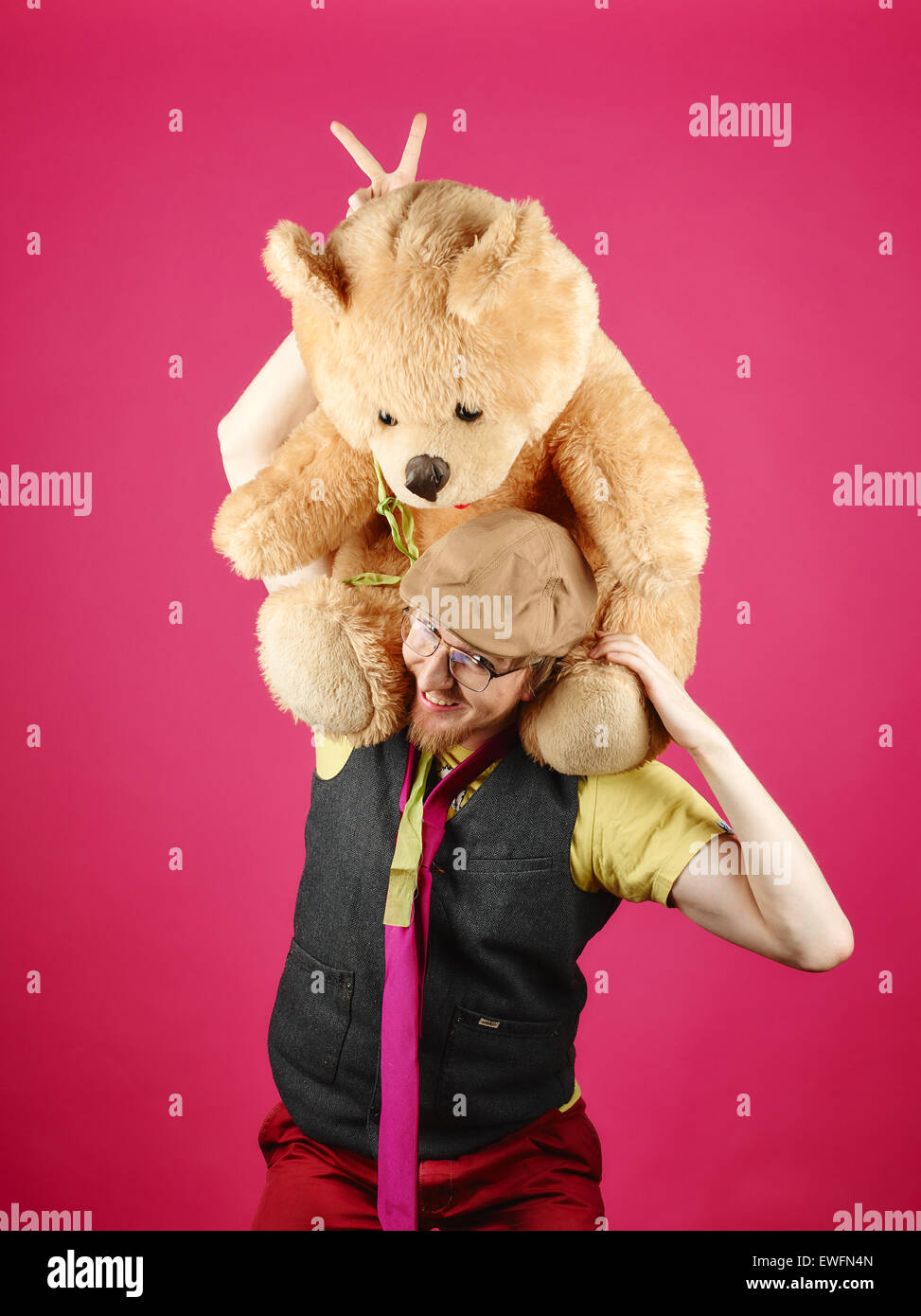 Expressive hipster wearing a vest and pink tie and he holds teddy bear ...