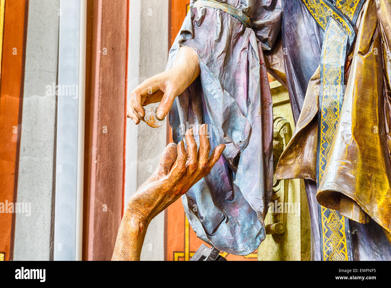 Carved wooden right hand of rich woman giving coin to left hand of poor ...