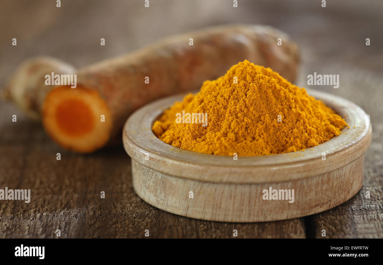 Raw and ground turmeric on wooden surface Stock Photo - Alamy