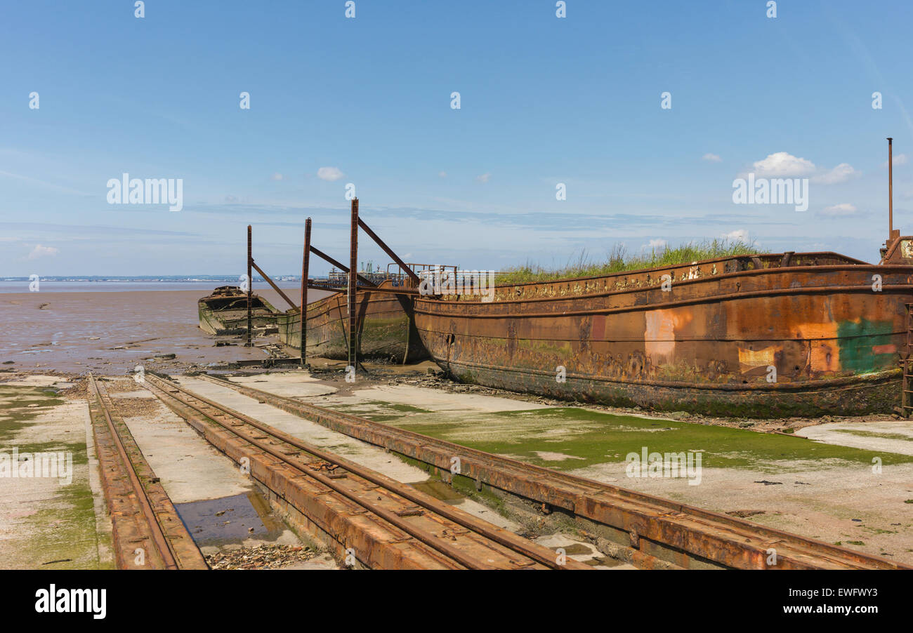Disused ship yard with derelict iron ships and rusting winch flanked by ...