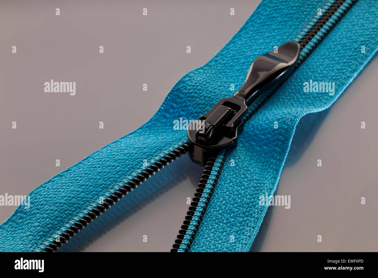 studio photography of blue zipper opened on a half to a gray surface ...