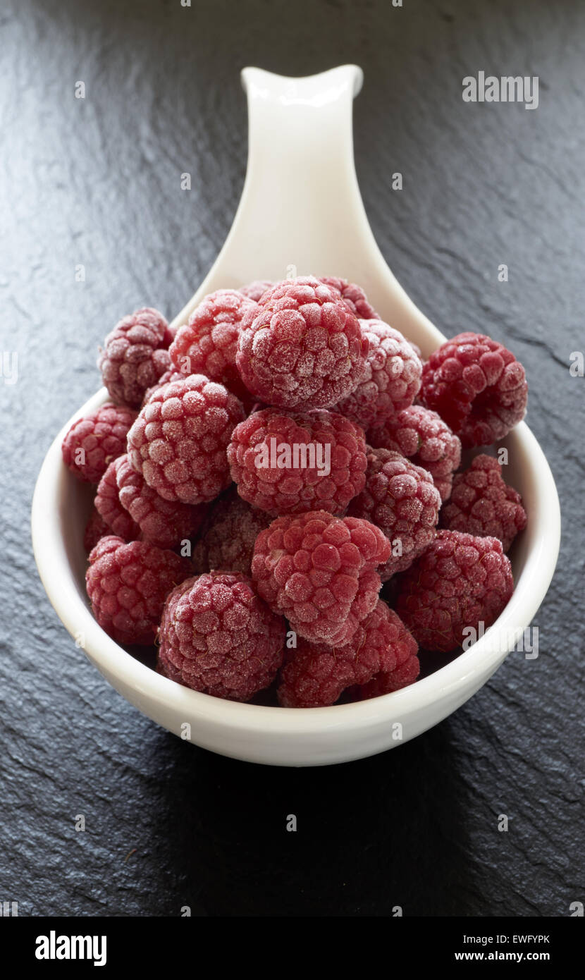 Close up of some frozen raspberries in a white porcelain dish on a ...