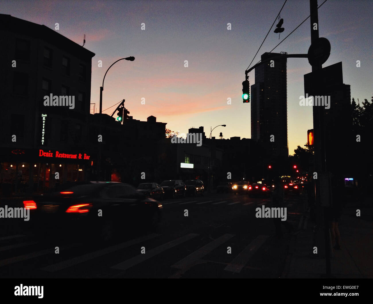 A city street scene at dusk, with streetlights beginning to glow and ...
