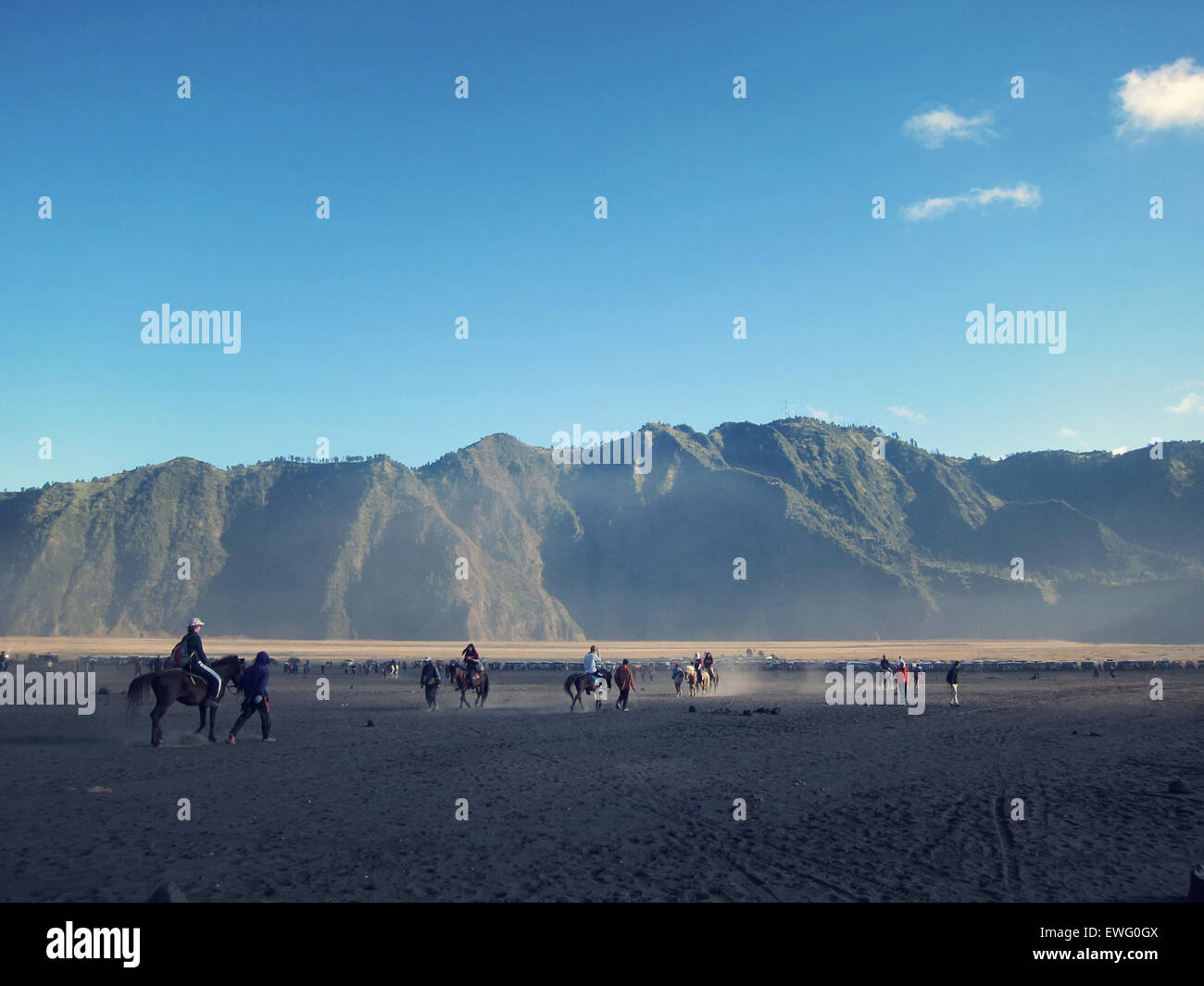This image depicts a mountain landscape with people riding horses. The ...
