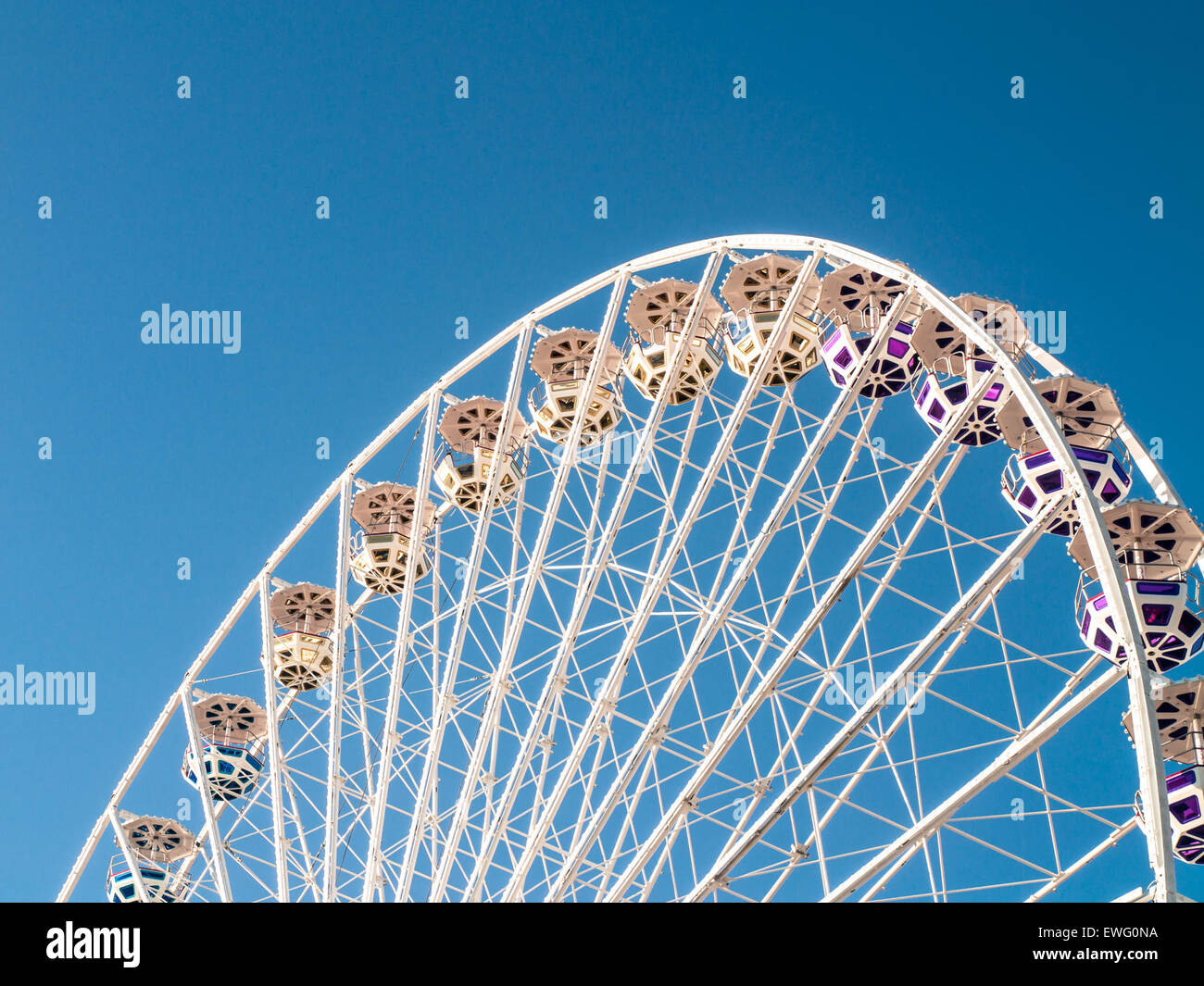 A Ferris wheel stands tall against a clear blue sky, with vibrant ...