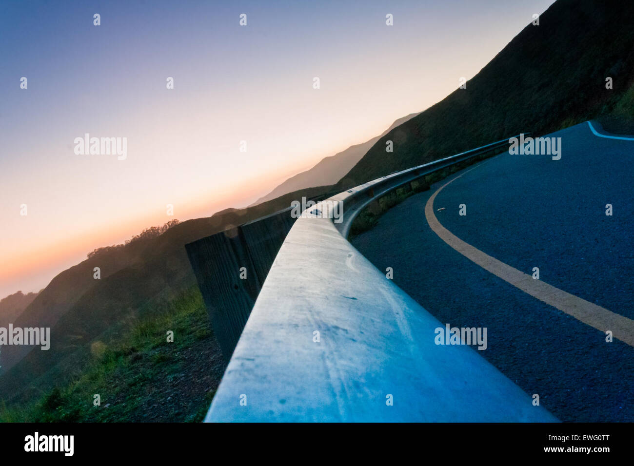 A guard rail is positioned along a curved road to provide safety for ...