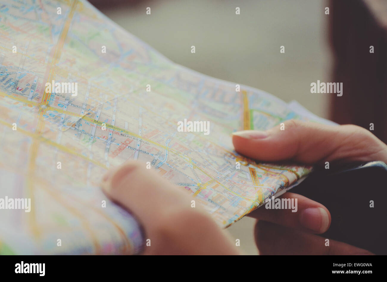 A pair of hands are holding a detailed street map, likely planning a ...