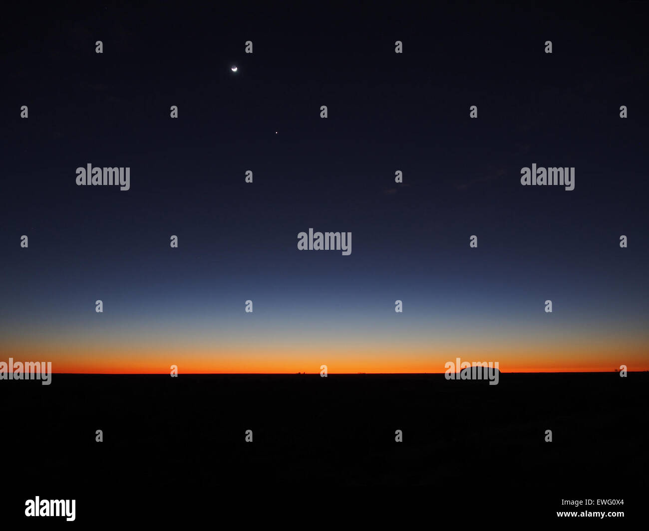A vast landscape at sunset captures the horizon, where the sun sets ...