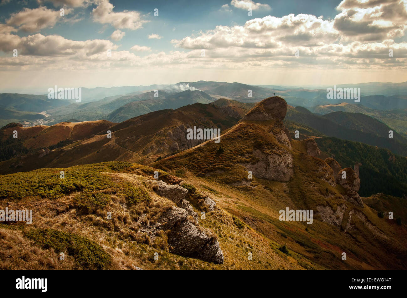 A person stands on top of a mountain, looking out over a vast landscape ...