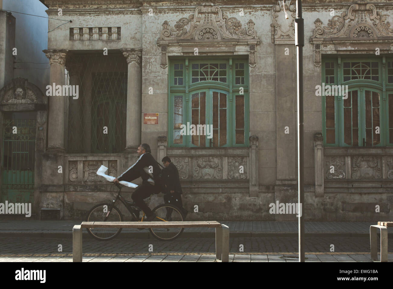 This image depicts a bicyclist outside an ornate building, with a bench ...
