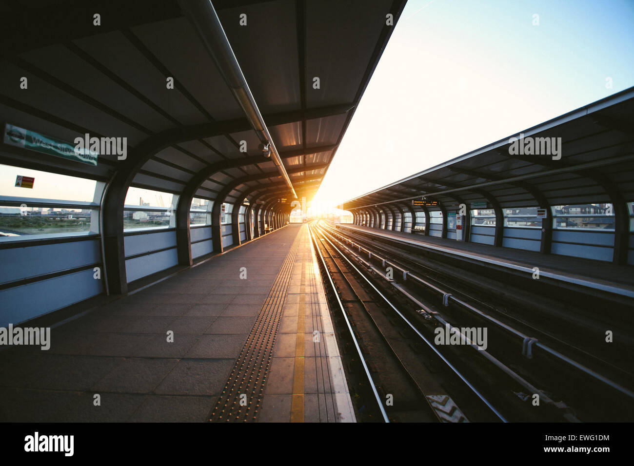 An outdoor train station at sunset features the silhouette of a train ...