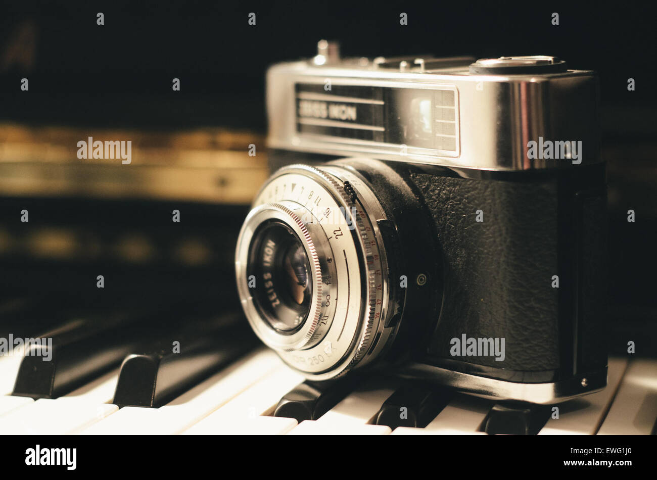 A black and silver camera resting on a piano keyboard, with the camera ...