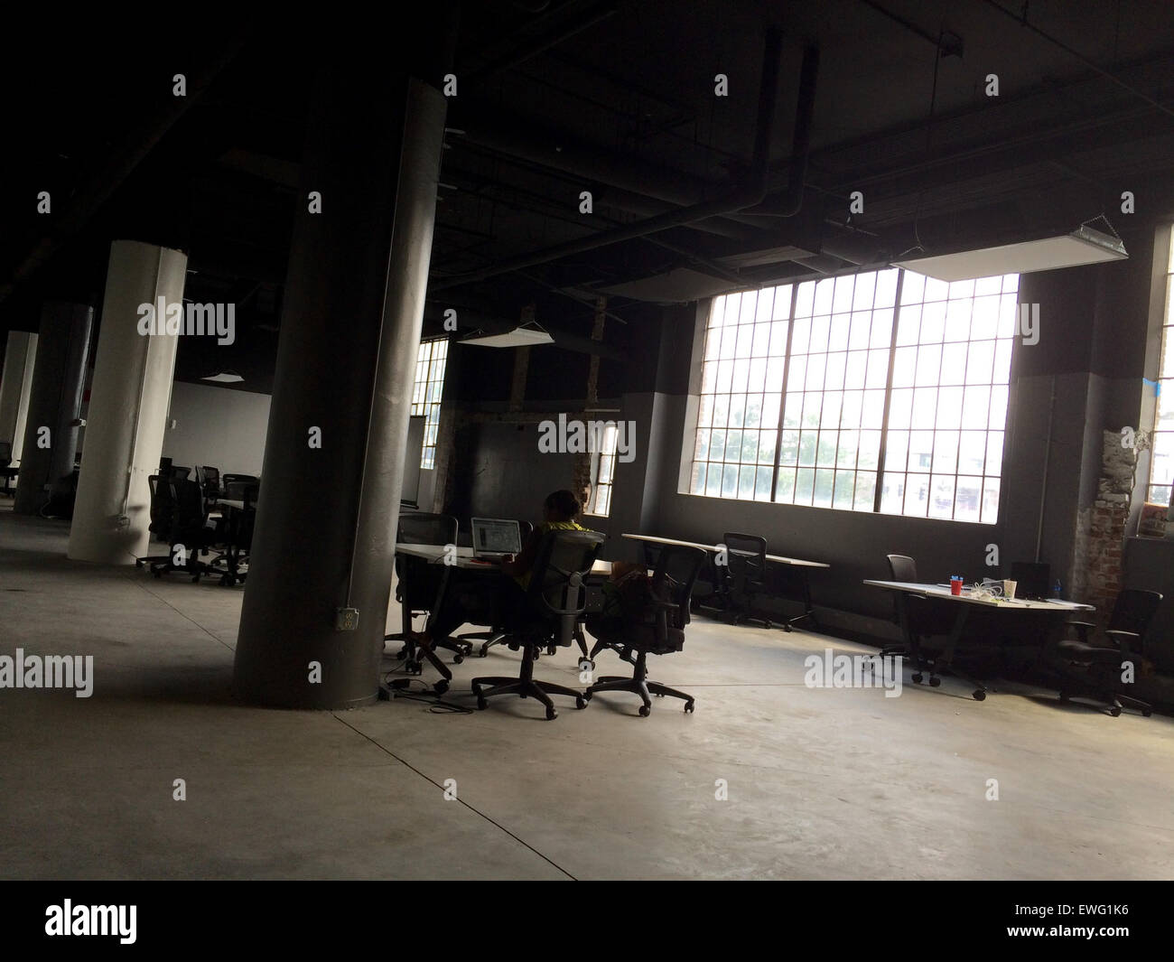 This image features a person sitting at an office desk in a warehouse ...