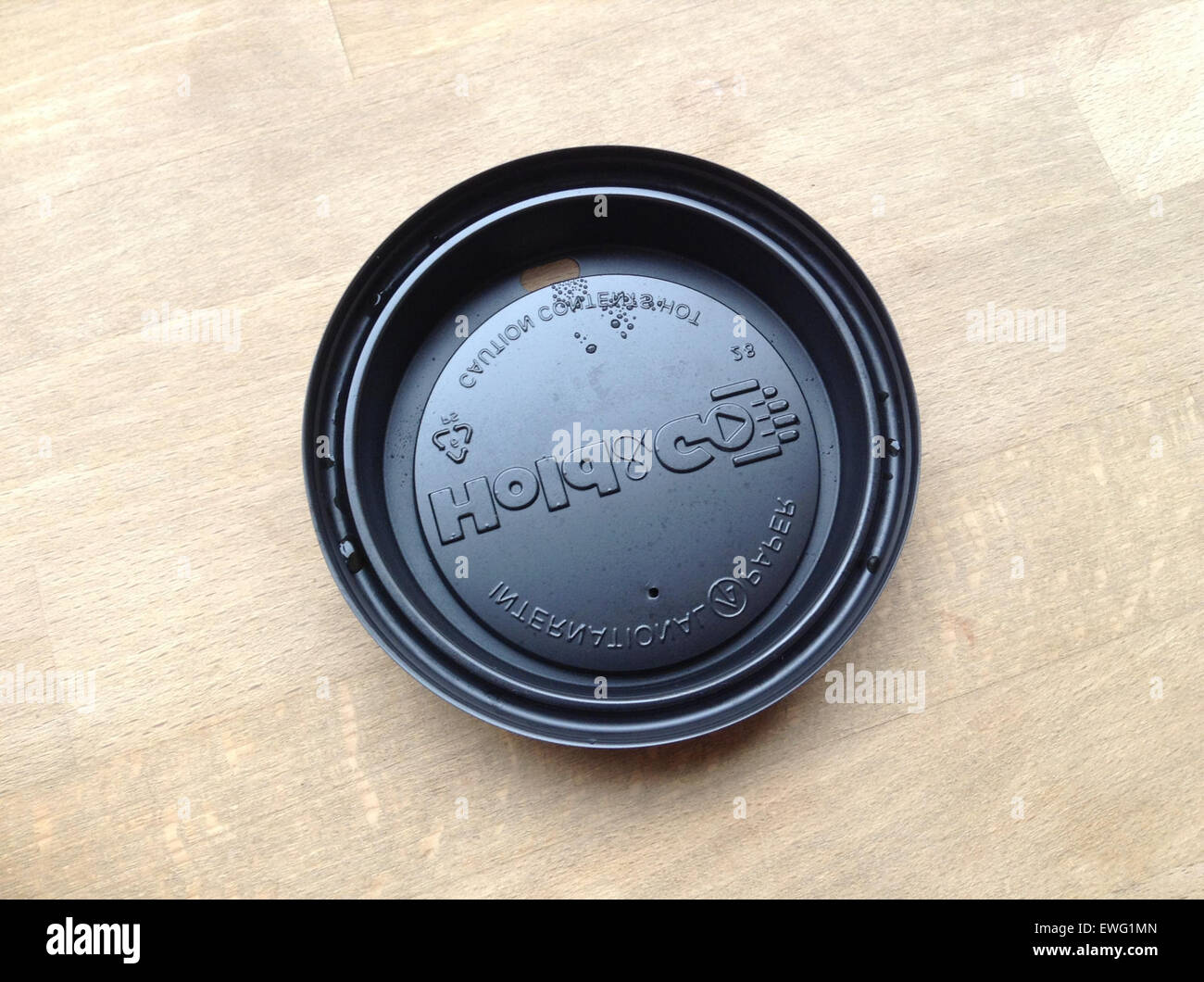 A plastic lid rests on a laminated wood tabletop. The lid contrasts ...