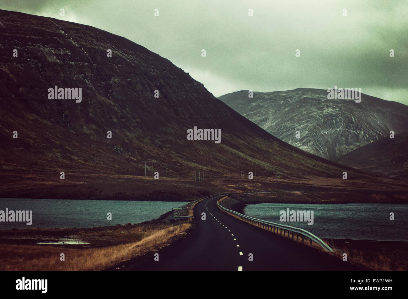 A road stretches over a lake, passing between two mountain ranges. The ...