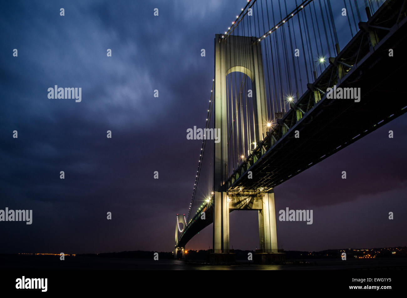 A scenic view of a bridge lit up at night, with clouds above and an ...