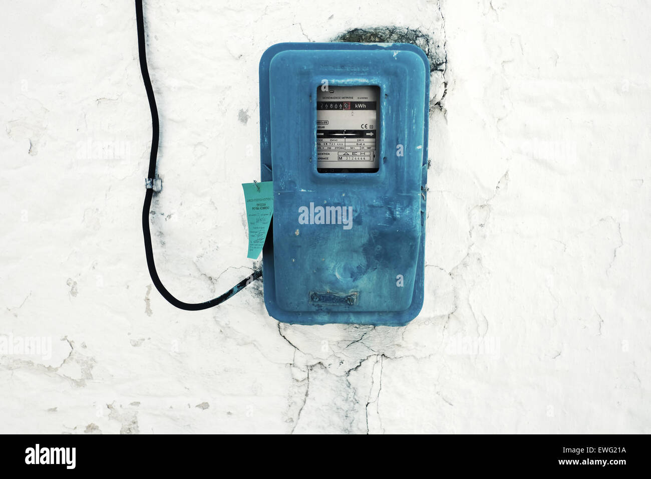 A blue box power meter with an attached wire mounted on a white wall ...