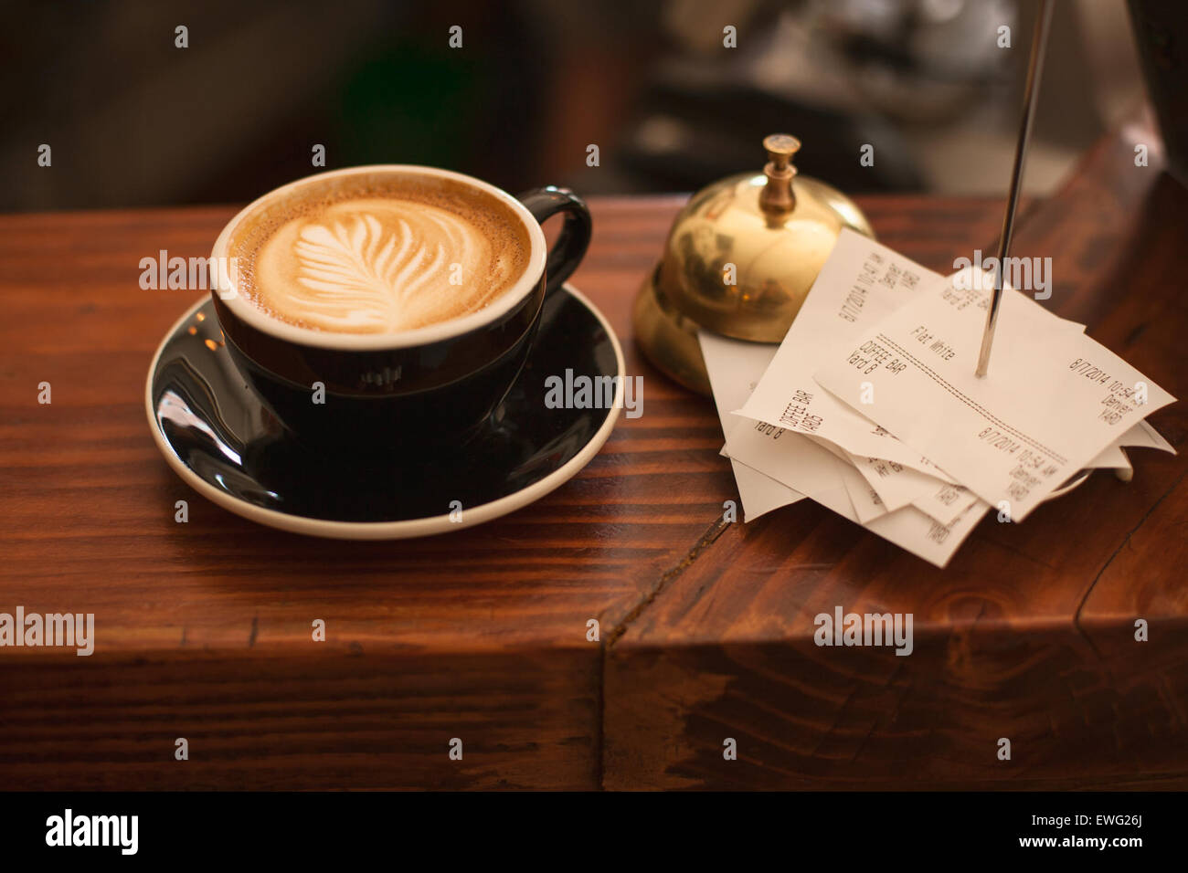 This image features a cappuccino in a cup placed on a cafe counter. The ...