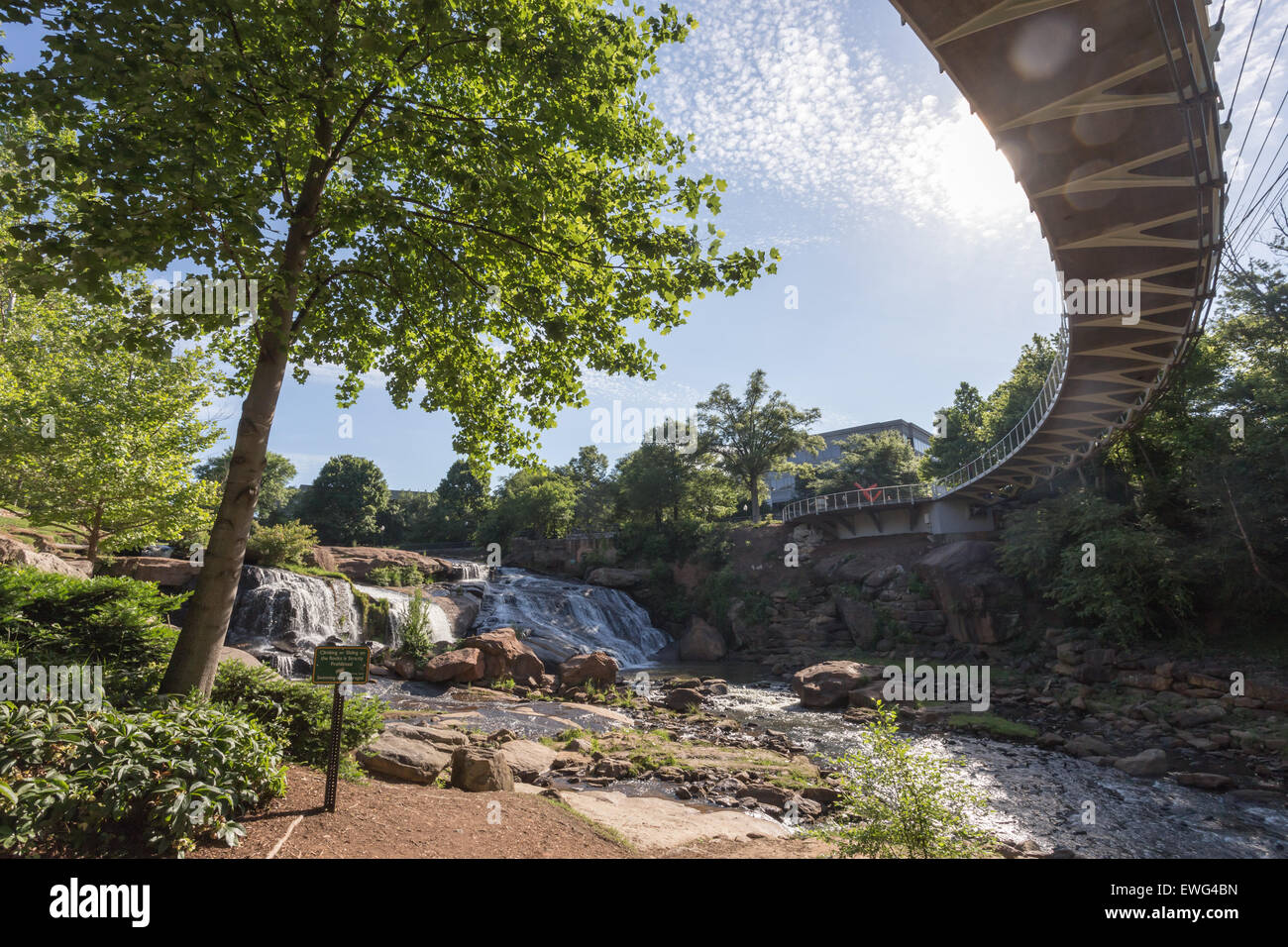 The Liberty bridge, a curved suspension bridge, crosses the Reedy River falls in beautiful and ...