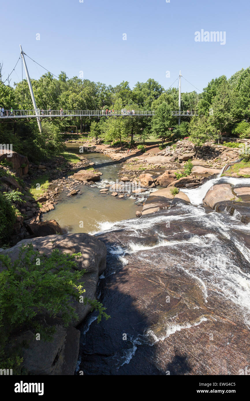 The Liberty bridge, a curved suspension bridge, crosses the Reedy River falls in beautiful and ...