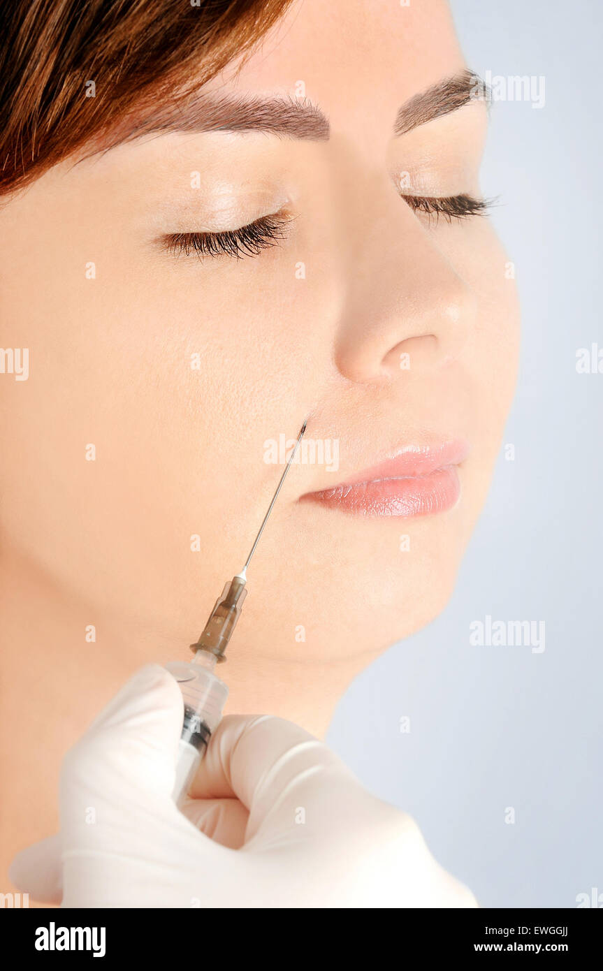 Woman applying botox on blue background Stock Photo - Alamy
