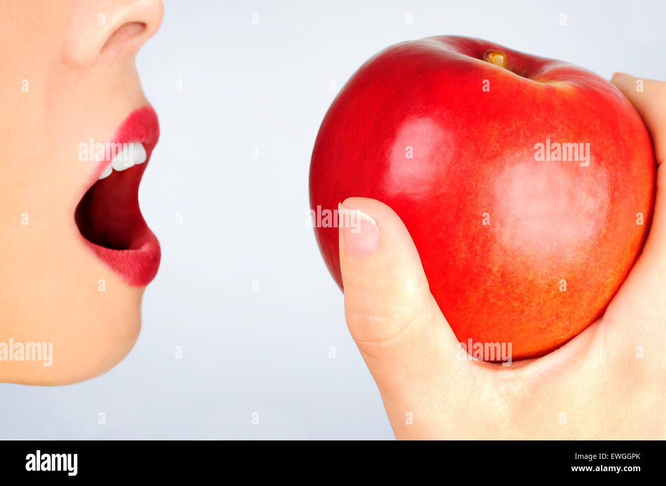 Girl eating apple on blue background Stock Photo - Alamy