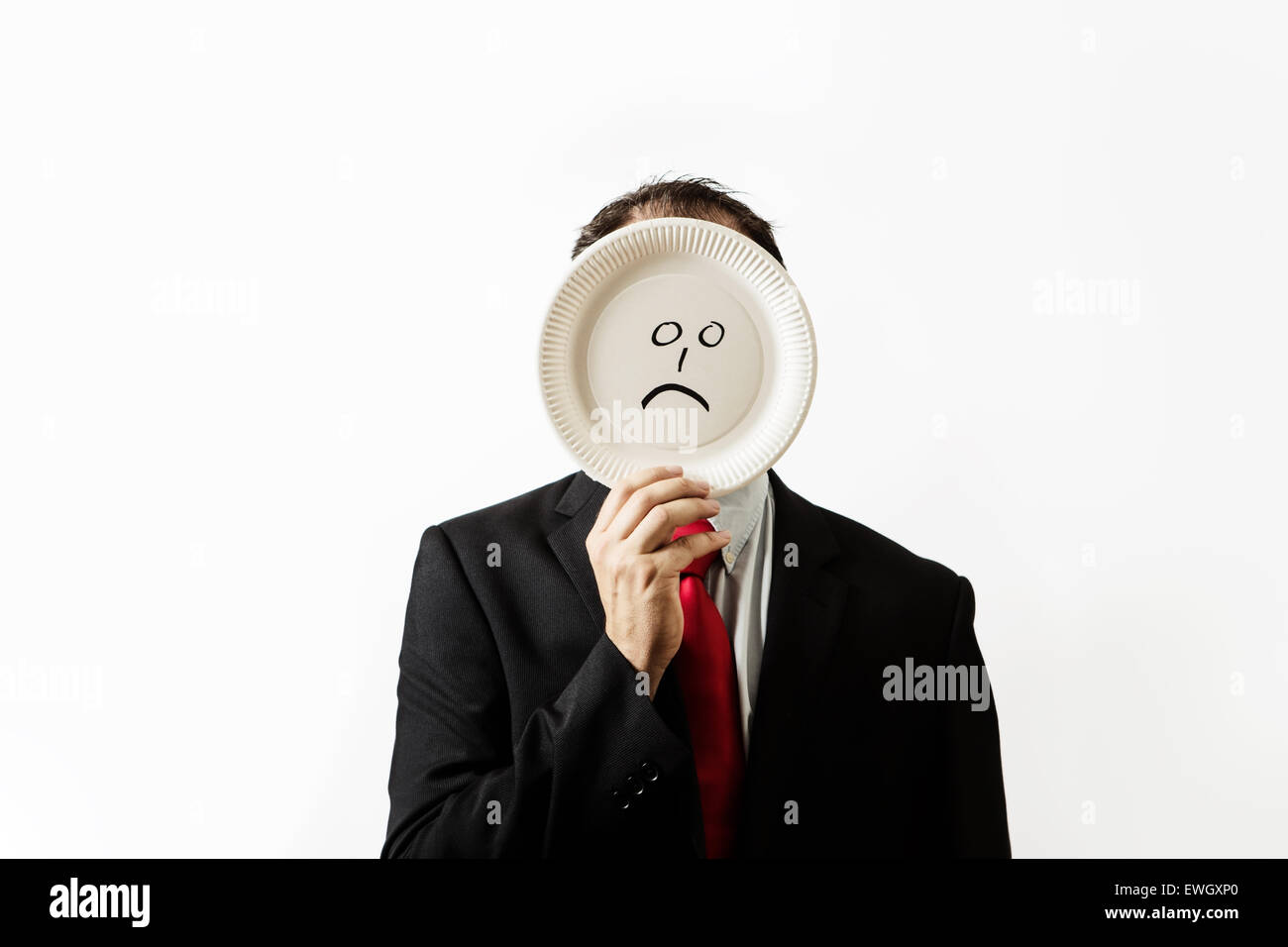 businessman holding a papper plate up to his face with a sad face draw ...