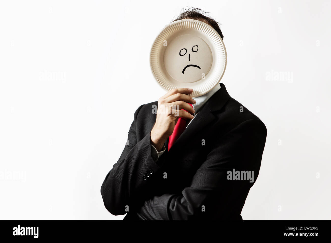businessman holding a papper plate up to his face with a sad face draw ...