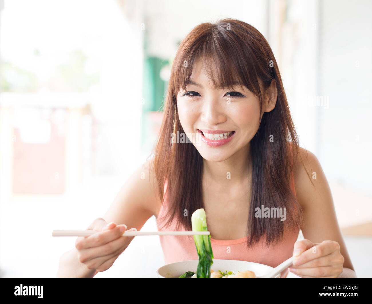 Asian girl eating vegetable noodles at Chinese restaurant. Young woman ...
