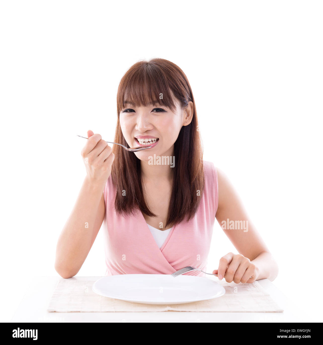 Asian girl having meal with fork and spoon, empty plate ready for food ...