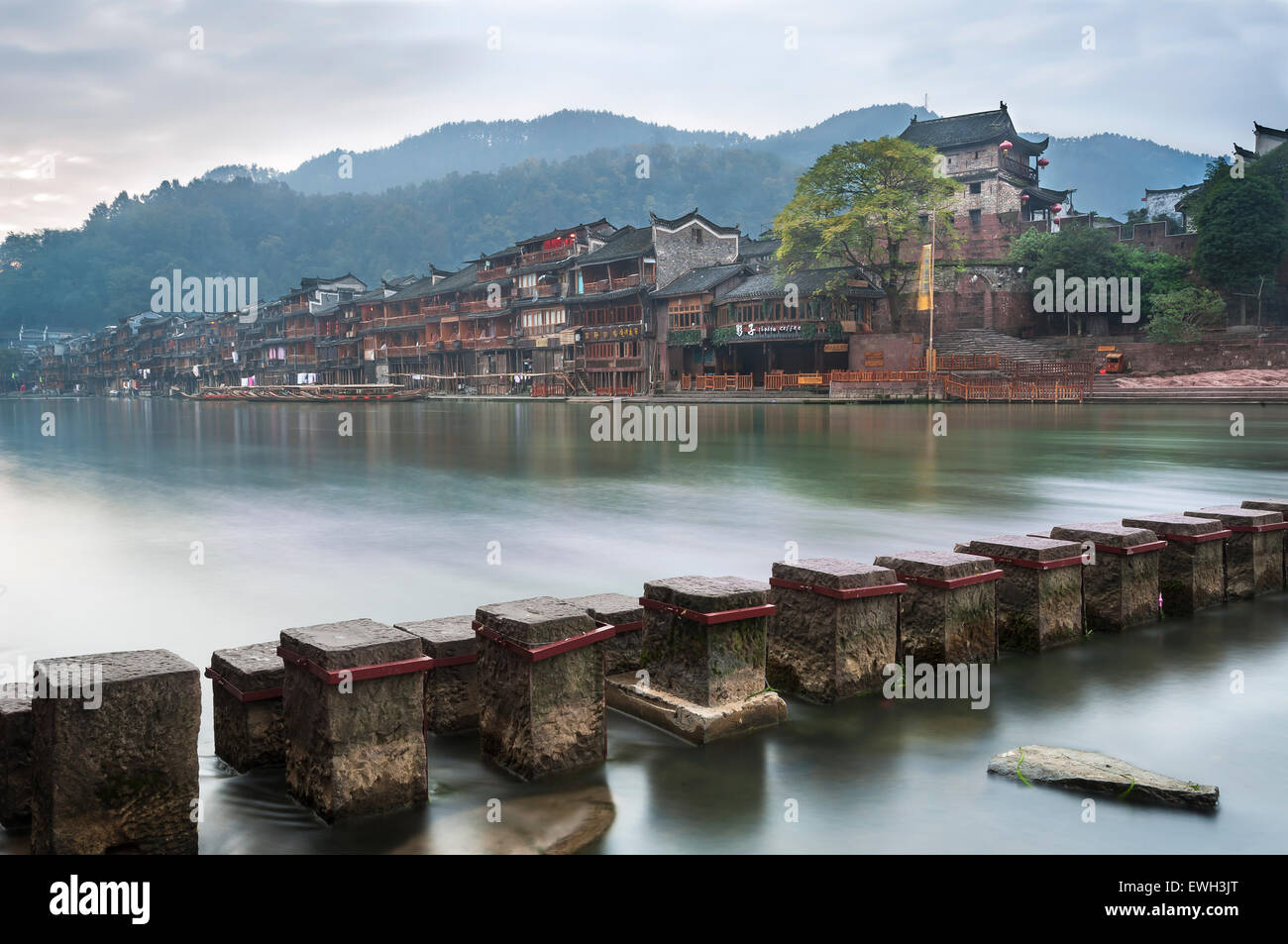 Stepping stones across the Tuojiang river with the North Gate Tower in ...