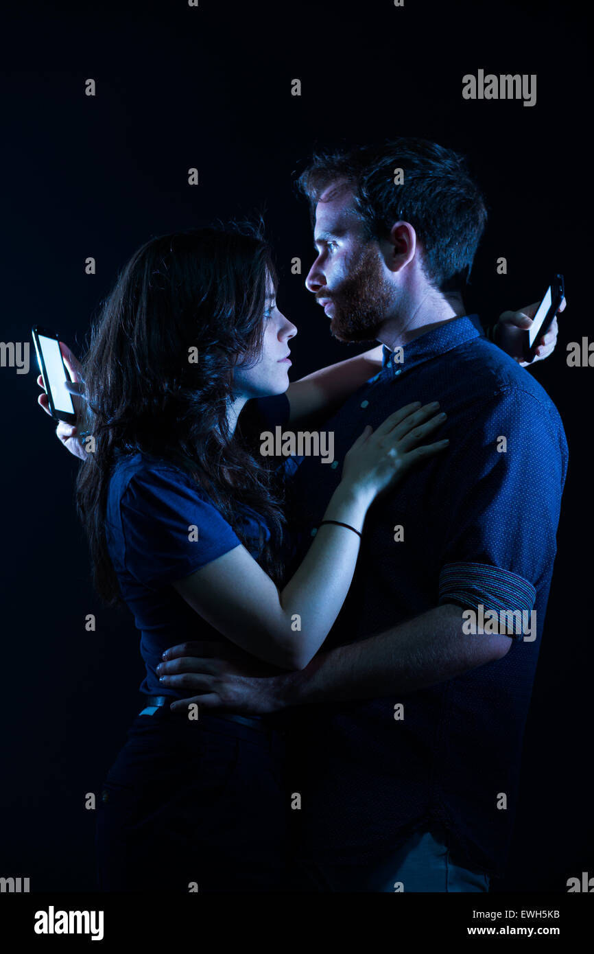 Young Silent Couple Hugging with Smartphones Stock Photo - Alamy