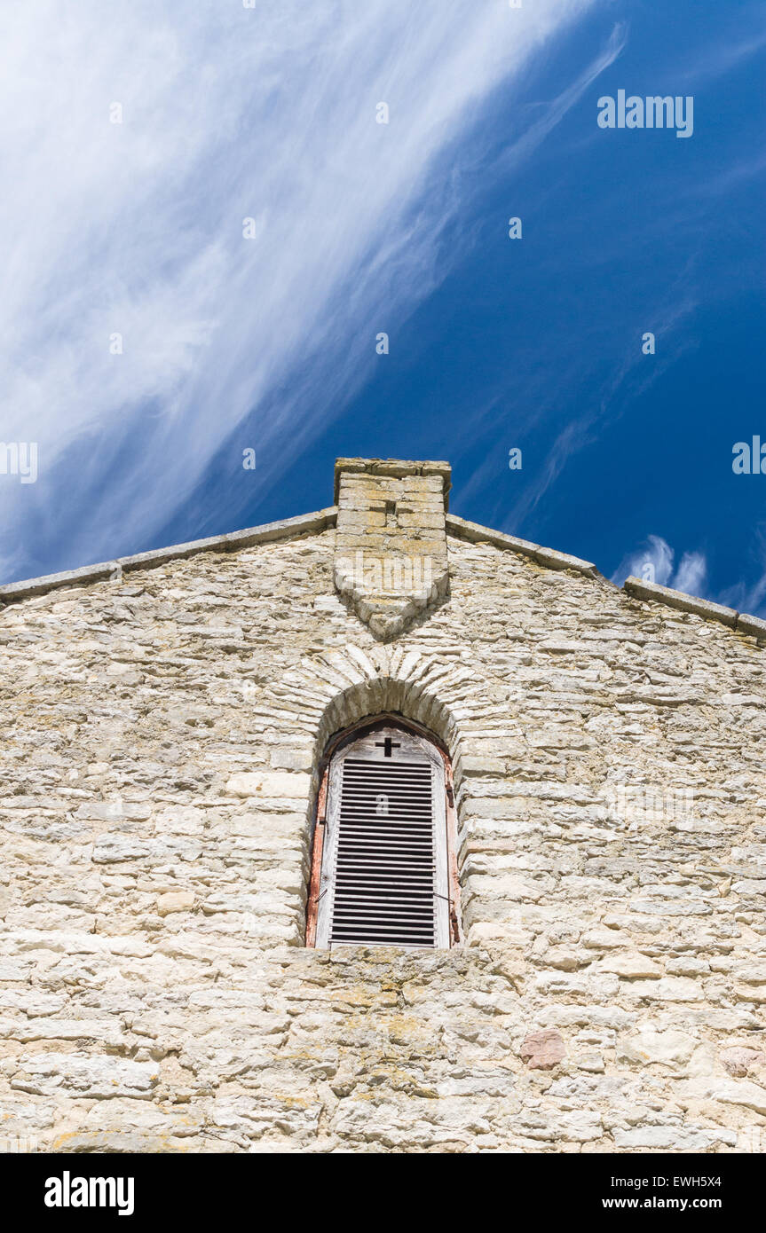 Limestone facade of ancient church with window shutter and cross shape ...