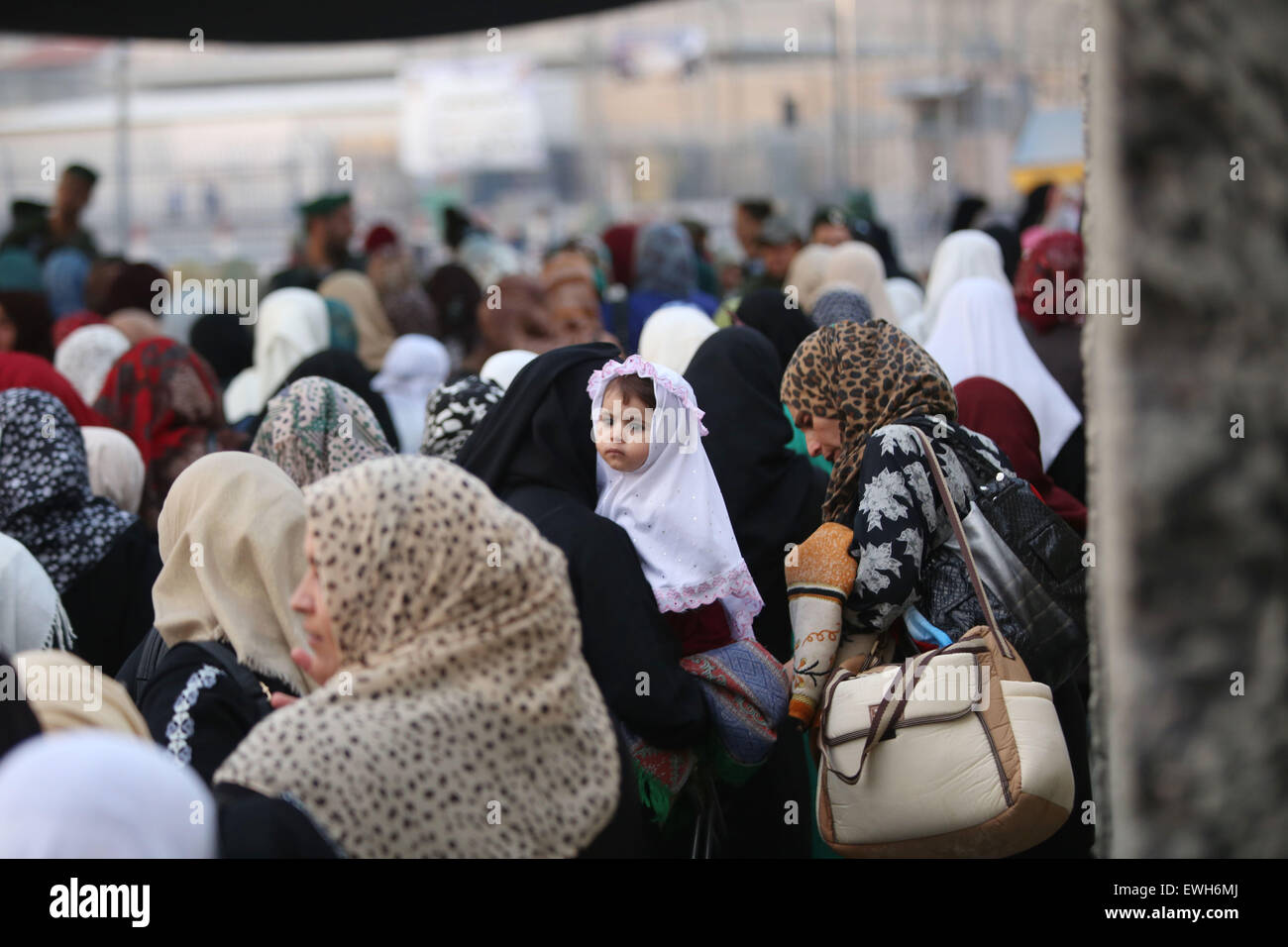 A Palestinian girl sits in the arms of her mother who tries to cross ...