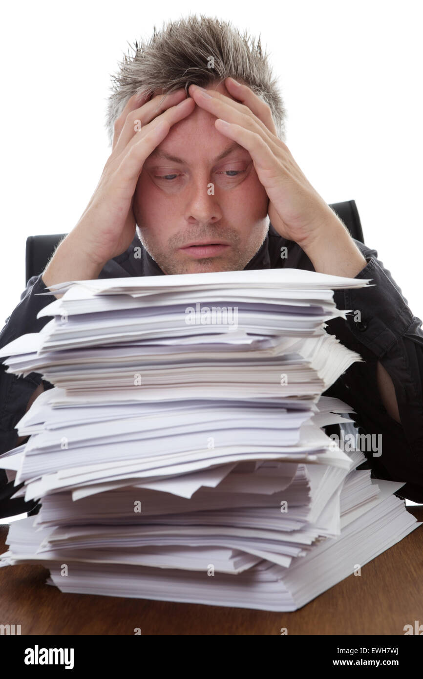 over worked businessman with a stack of paper work infront of him ...