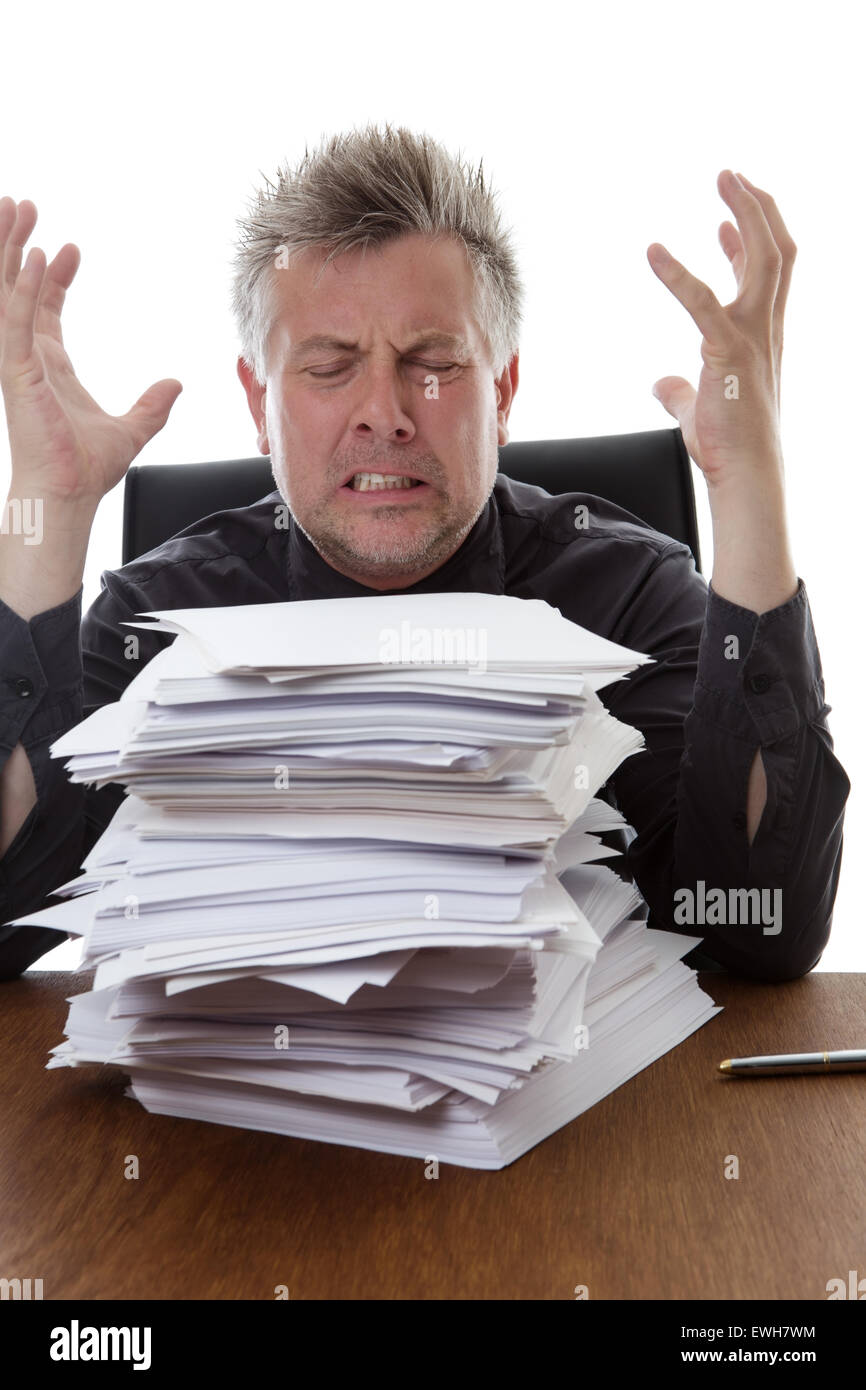 over worked businessman with a stack of paper work infront of him ...