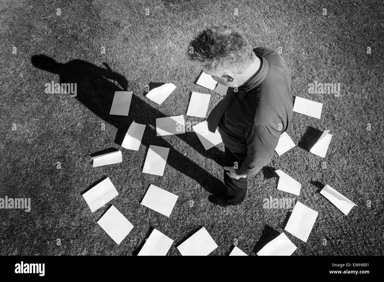 paper laid out on grass taken from above with a businessman standing in ...