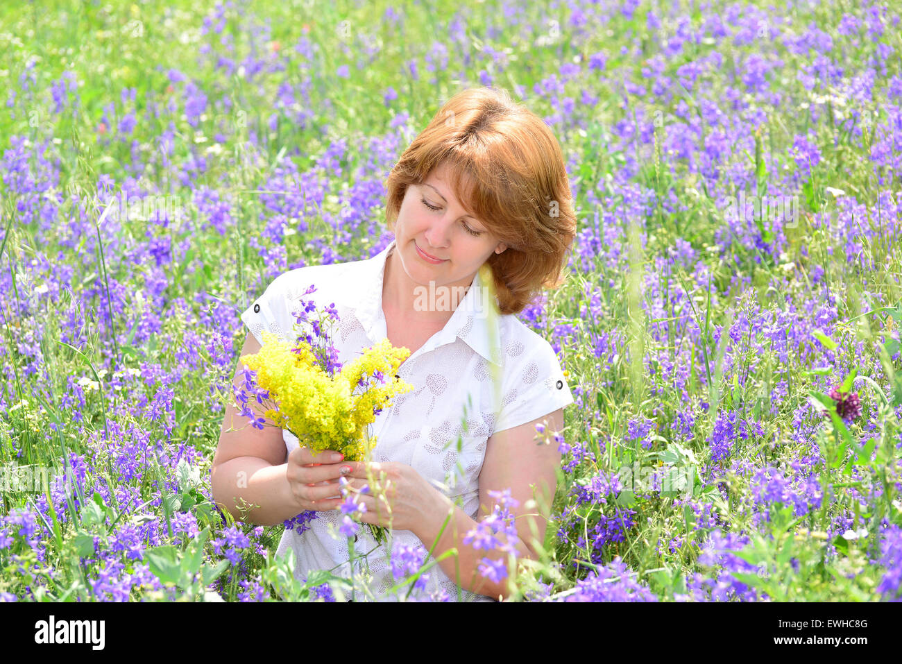 Adult woman in a meadow with wild flowers Stock Photo - Alamy