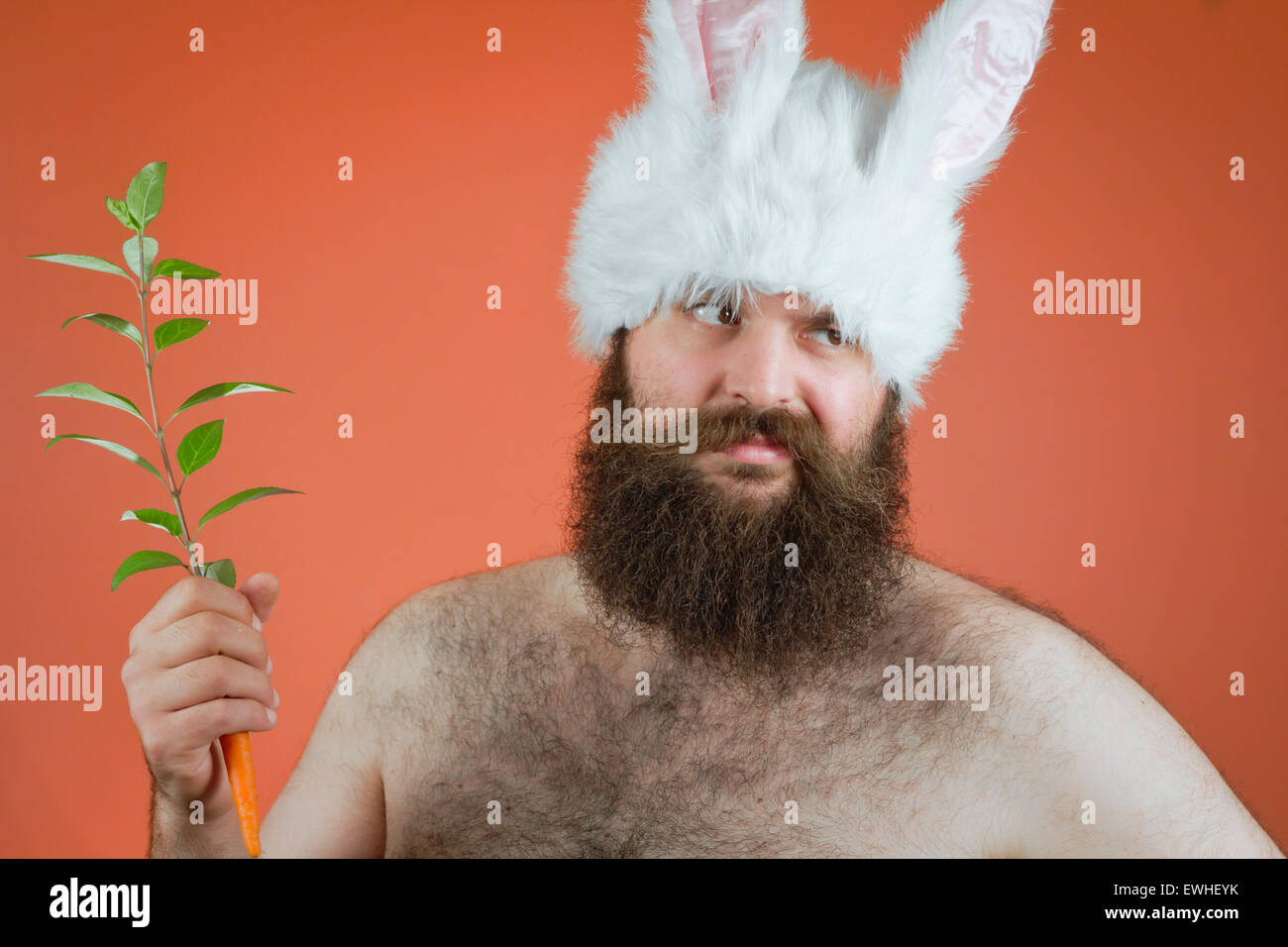 Disapproving man wearing bunny ears and holding carrot Stock Photo - Alamy