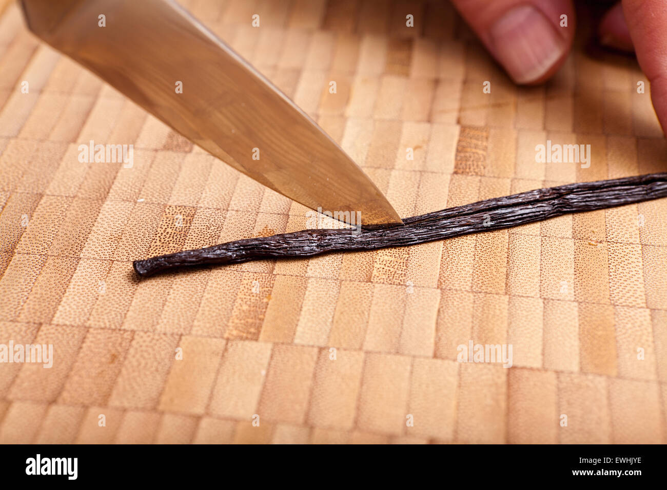 Cutting open the vanilla pod with a knife on bamboo cutting board Stock ...