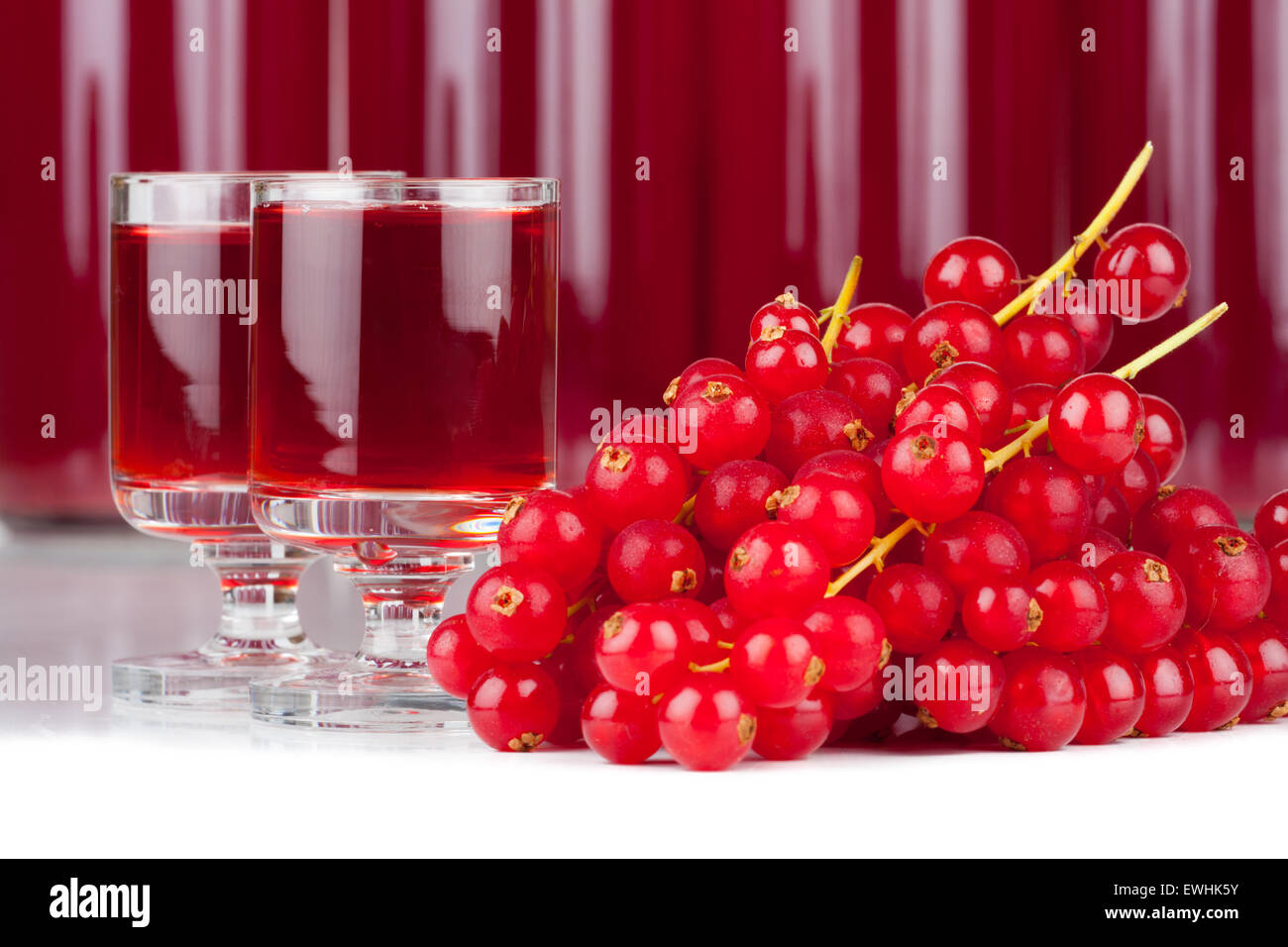 Close-up view of ripe red currants and syrup in a glass and bottles ...