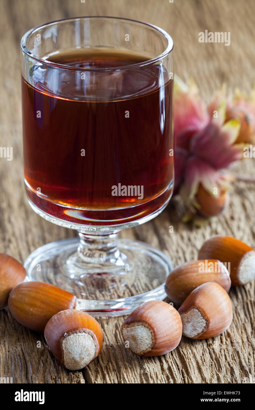 Homemade Hazelnut liqueur in a glass and hazelnuts of an old rustic ...