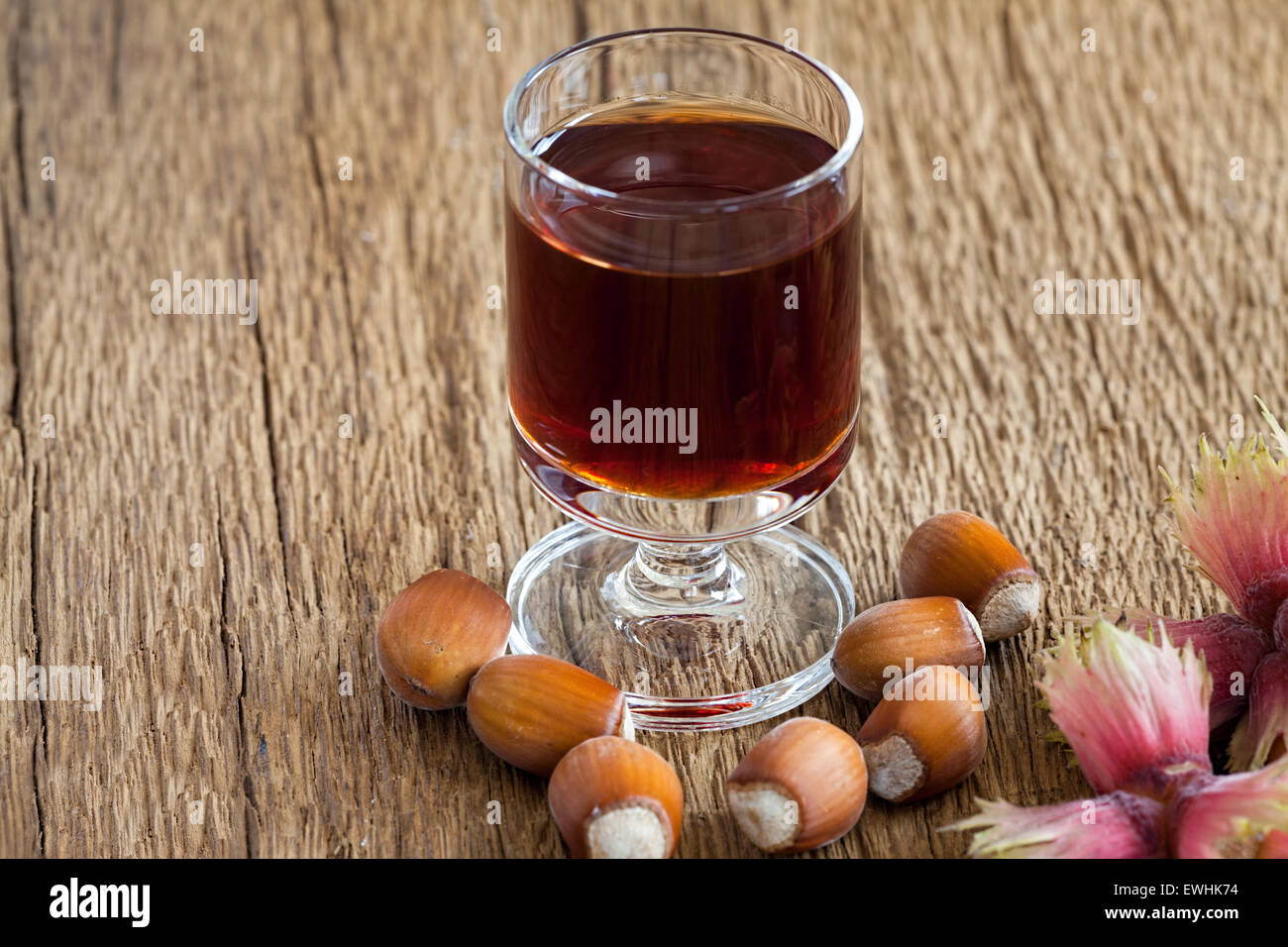 Homemade Hazelnut liqueur in a glass and hazelnuts of an old rustic ...