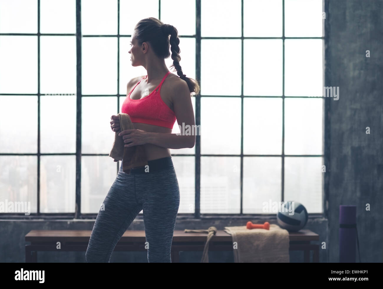 A fit, strong, muscular woman stands looking over her shoulder, out the ...