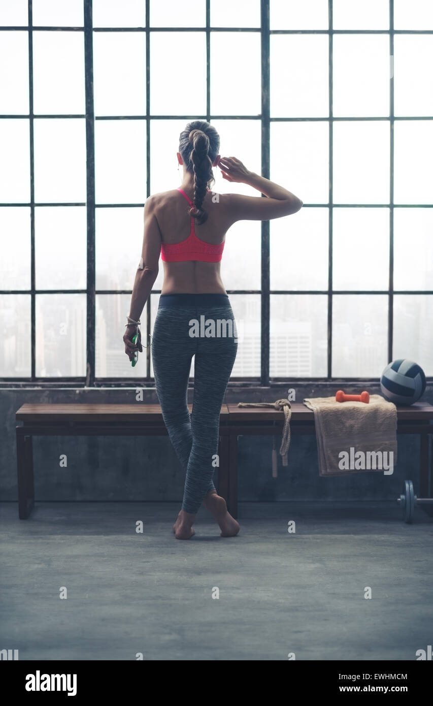 A fit, strong, muscular woman is standing, legs crossed, while looking ...