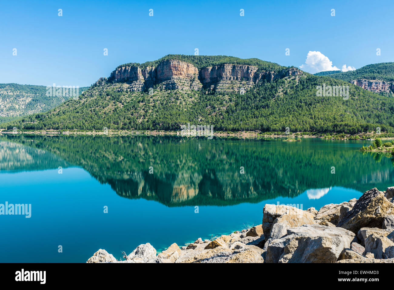Mountains and vegetation reflected on the calm water of a reservoir in ...
