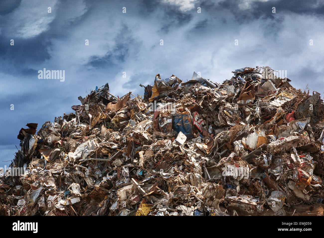 Scrap metal ready for recycling over dark clouds Stock Photo - Alamy