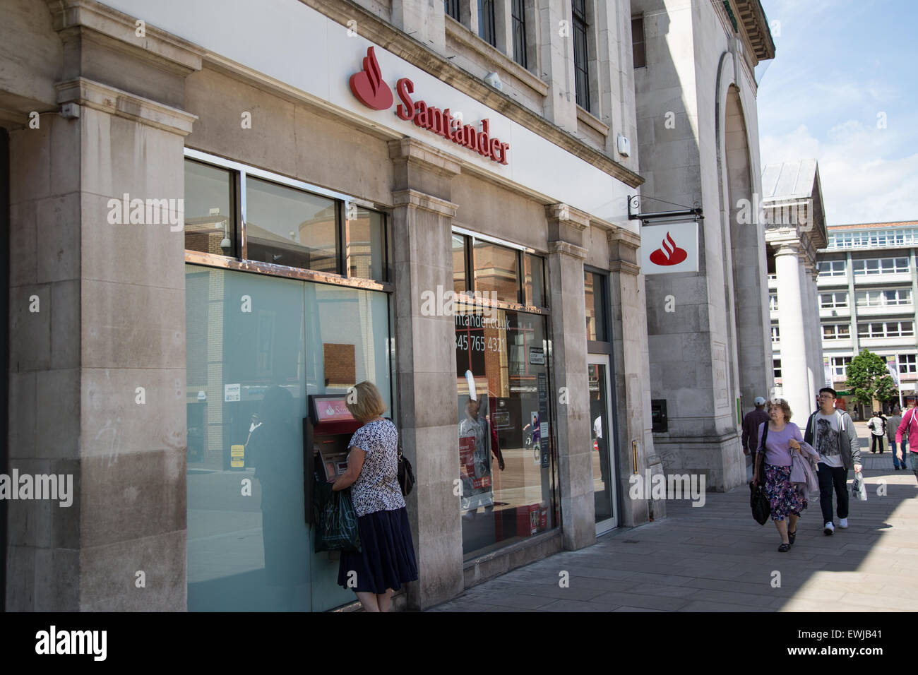 A woman at a cash point outside a branch of Santander bank Stock Photo ...
